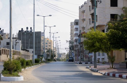 Palestinian policemen wear face masks, guard a barrier blocking a road ...