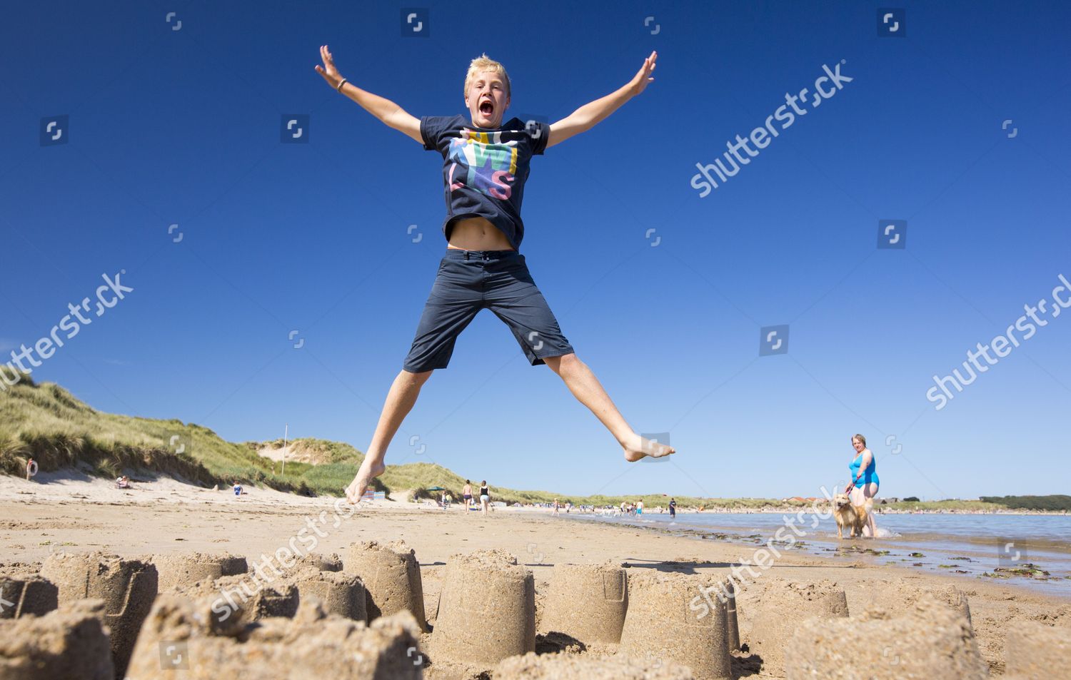 Boy Jumping Over Sandcastle On Bamburgh Editorial Stock Photo - Stock ...